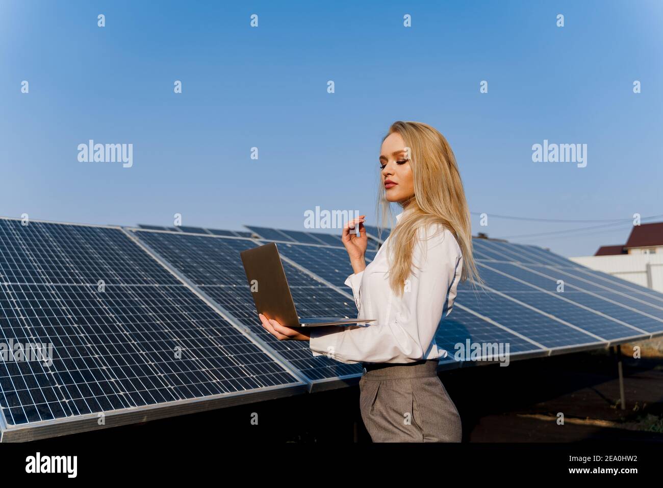 Investor and solar panels. Blonde woman with laptop near blue solar ...
