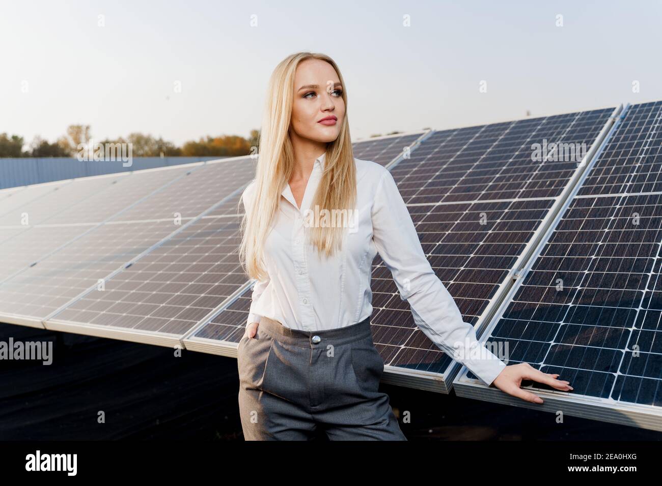Blonde model with solar panels stands in row on the ground. Girl ...