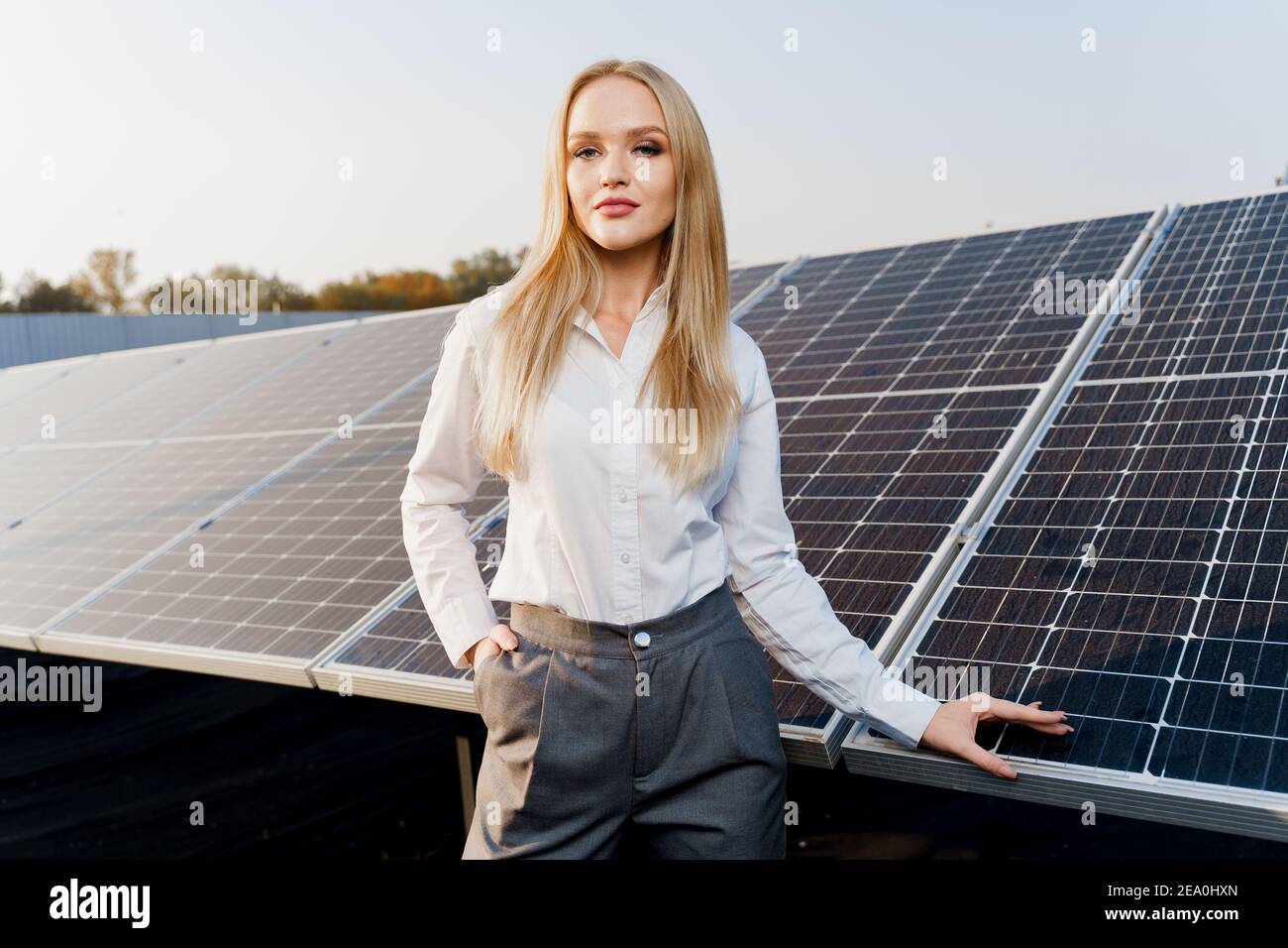 Blonde model with solar panels stands in row on the ground. Girl ...