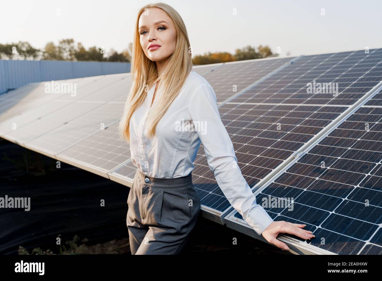 Blonde model with solar panels stands in row on the ground. Girl ...
