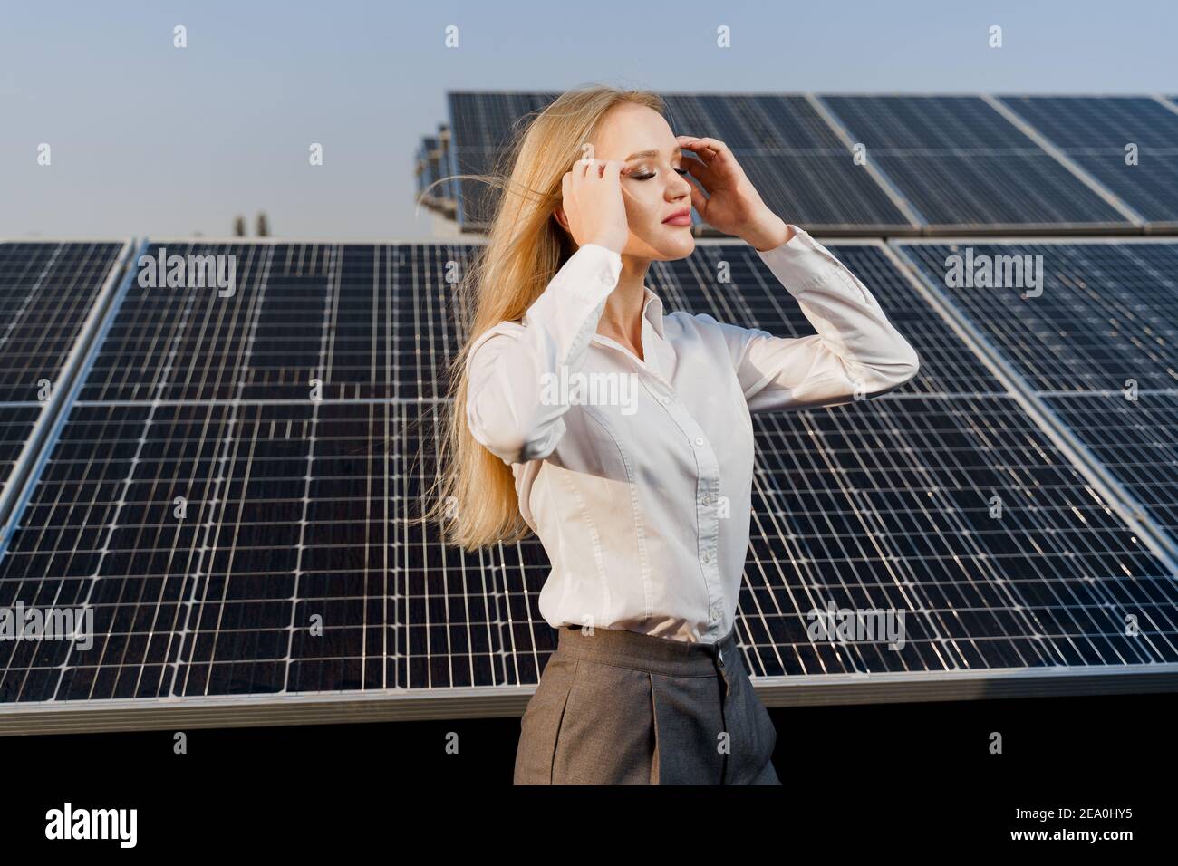 Blonde model with solar panels stands in row on the ground. Girl ...