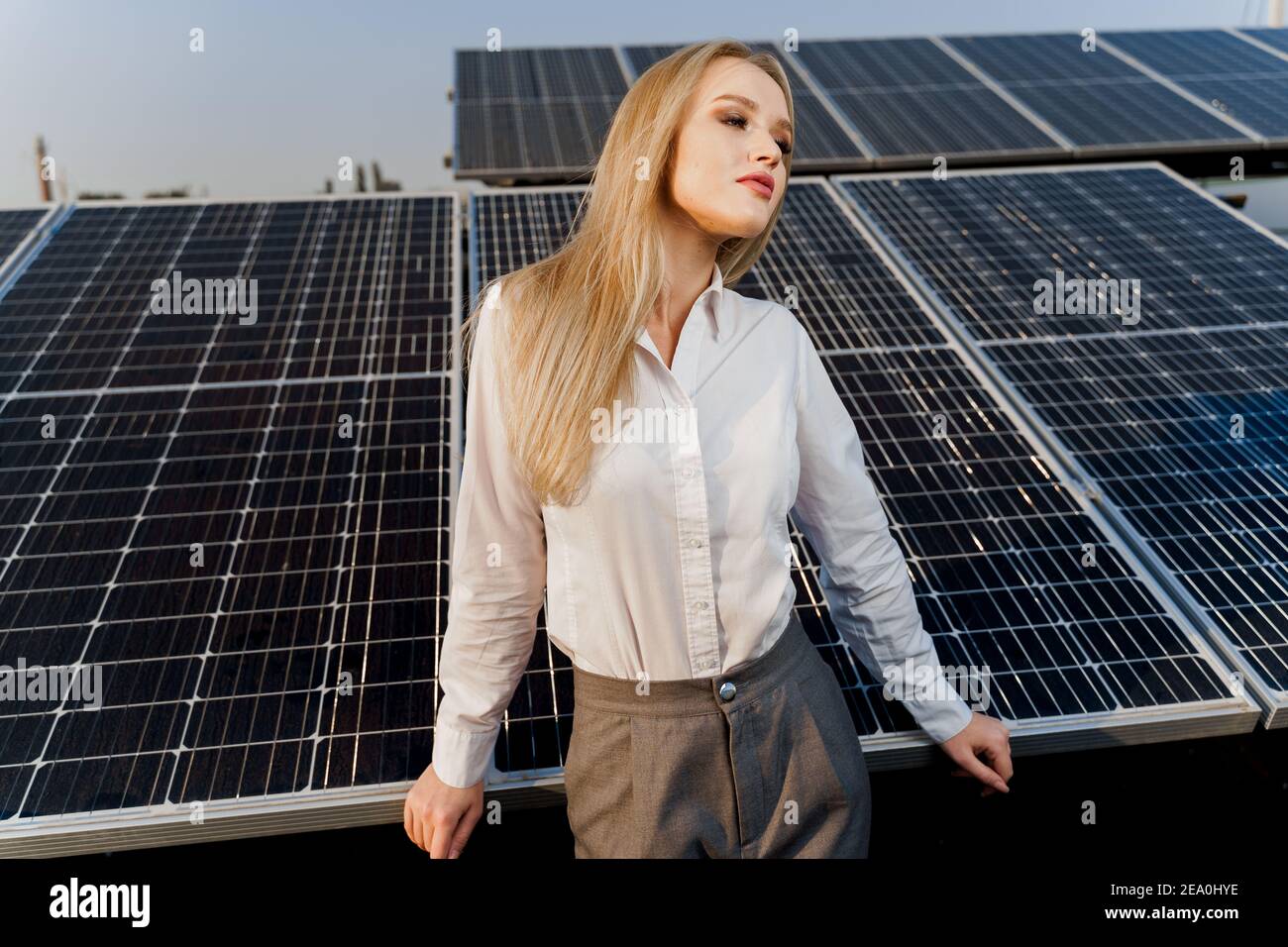 Blonde model with solar panels stands in row on the ground. Girl ...