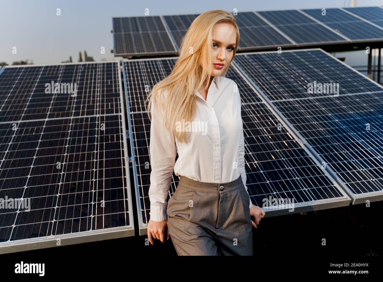 Blonde model with solar panels stands in row on the ground. Girl ...
