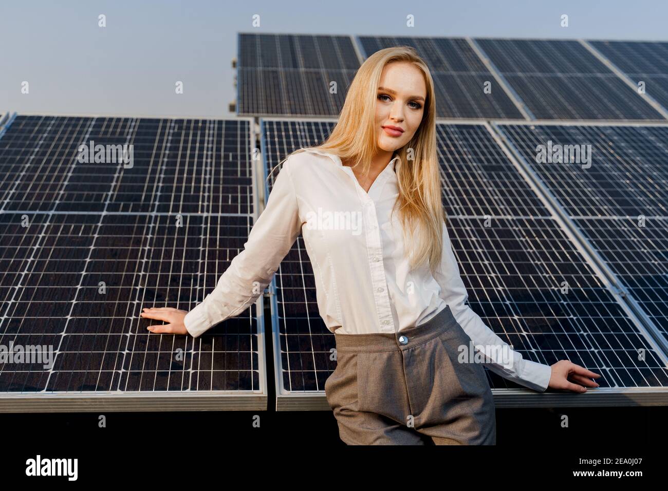 Blonde model with solar panels stands in row on the ground. Girl ...