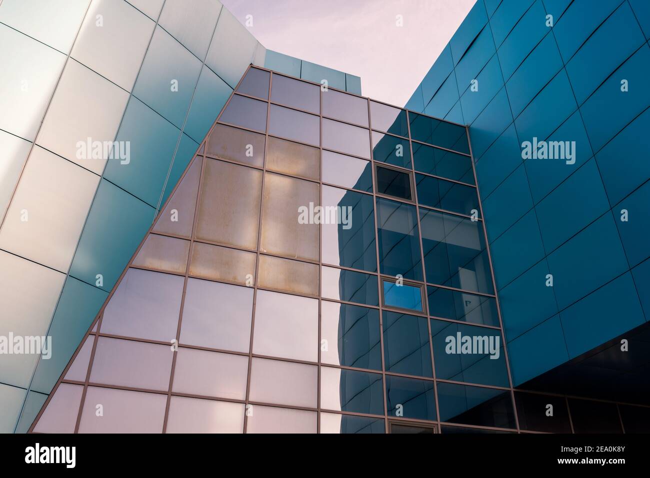 mirrored windows of the facade of an office building with blue panels ...