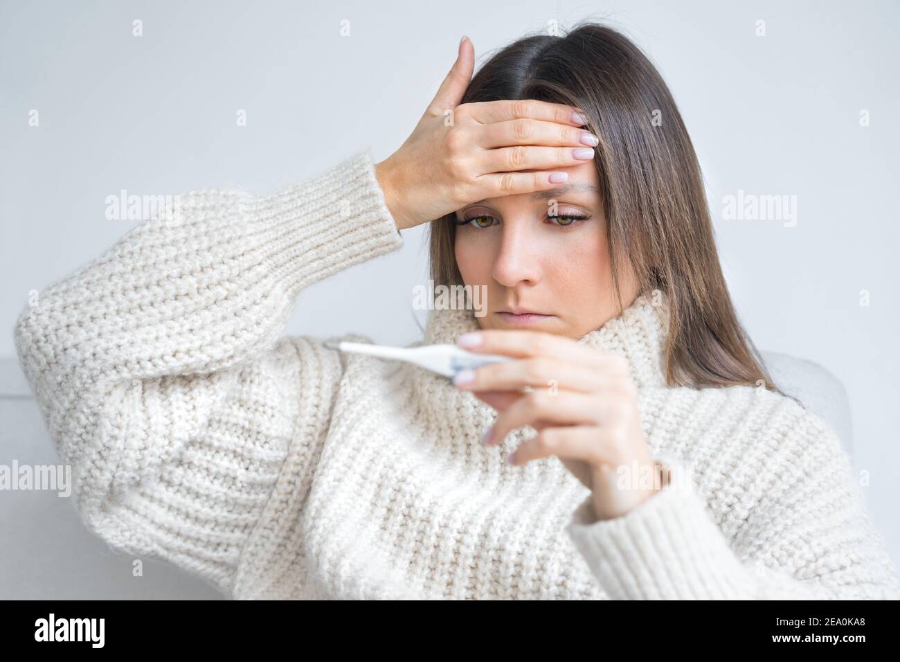 Sick unhealthy woman with fever holding a medical thermometer in her ...