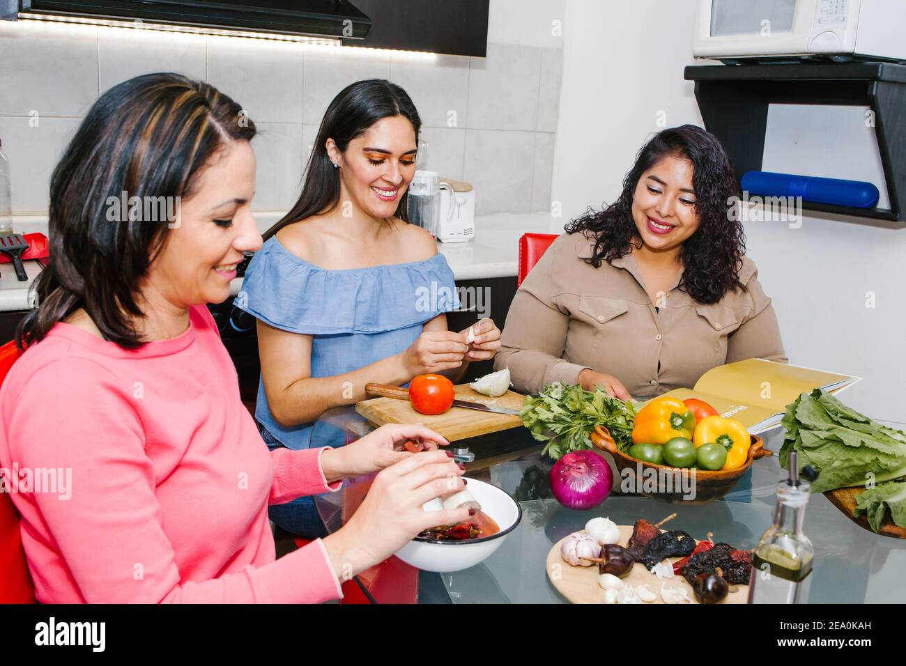 Three hispanic Female Friends cooking vegetables in a mexican Kitchen ...
