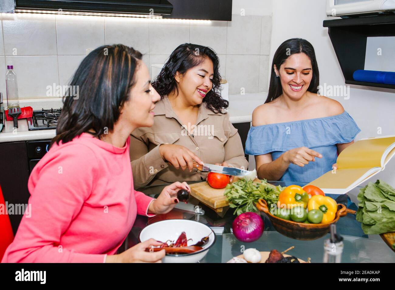 Three hispanic Female Friends cooking vegetables in a mexican Kitchen ...