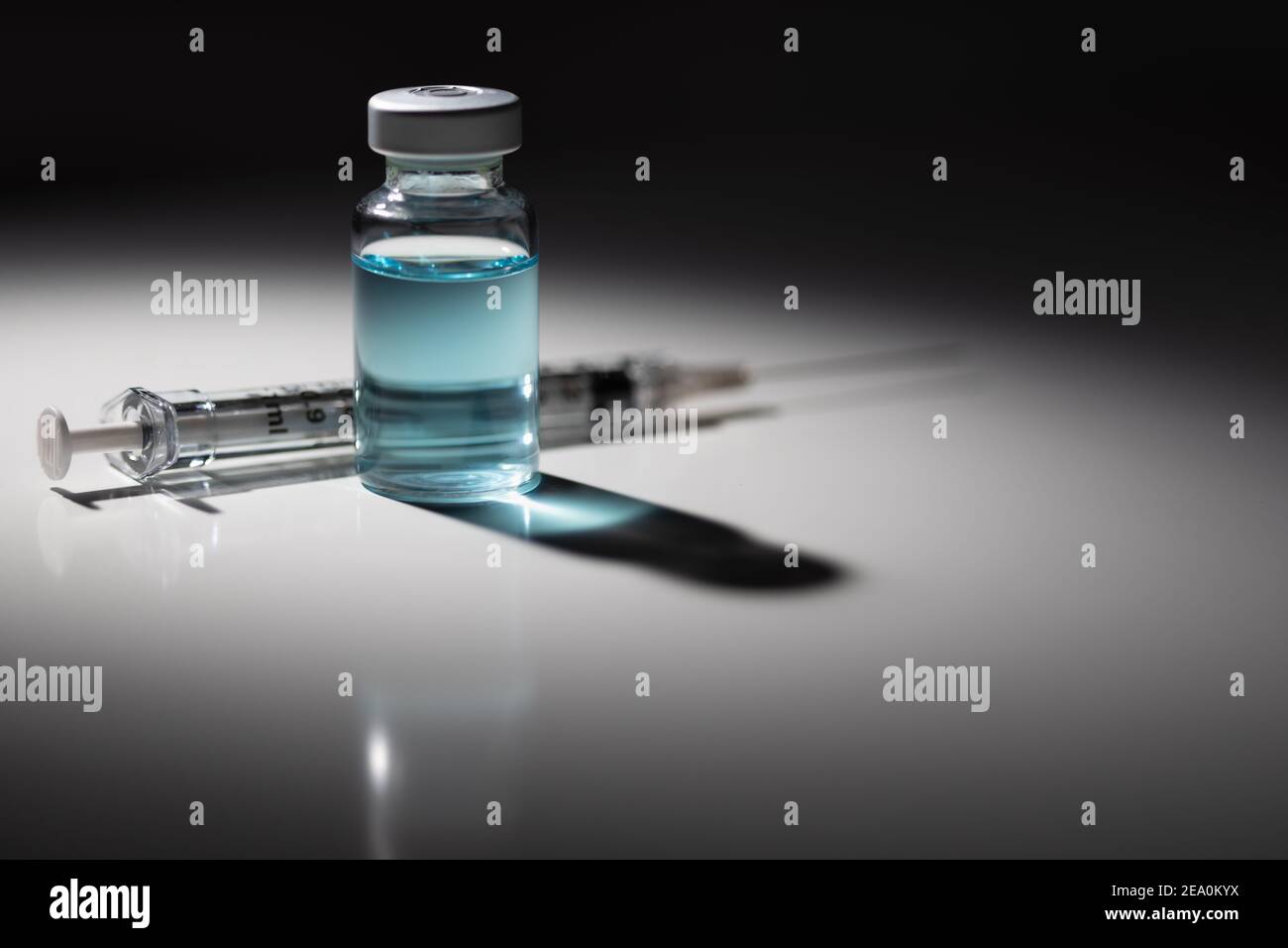 Syringe Needle and Medicine Vial With Light Blue Chemical Spot Lit on ...