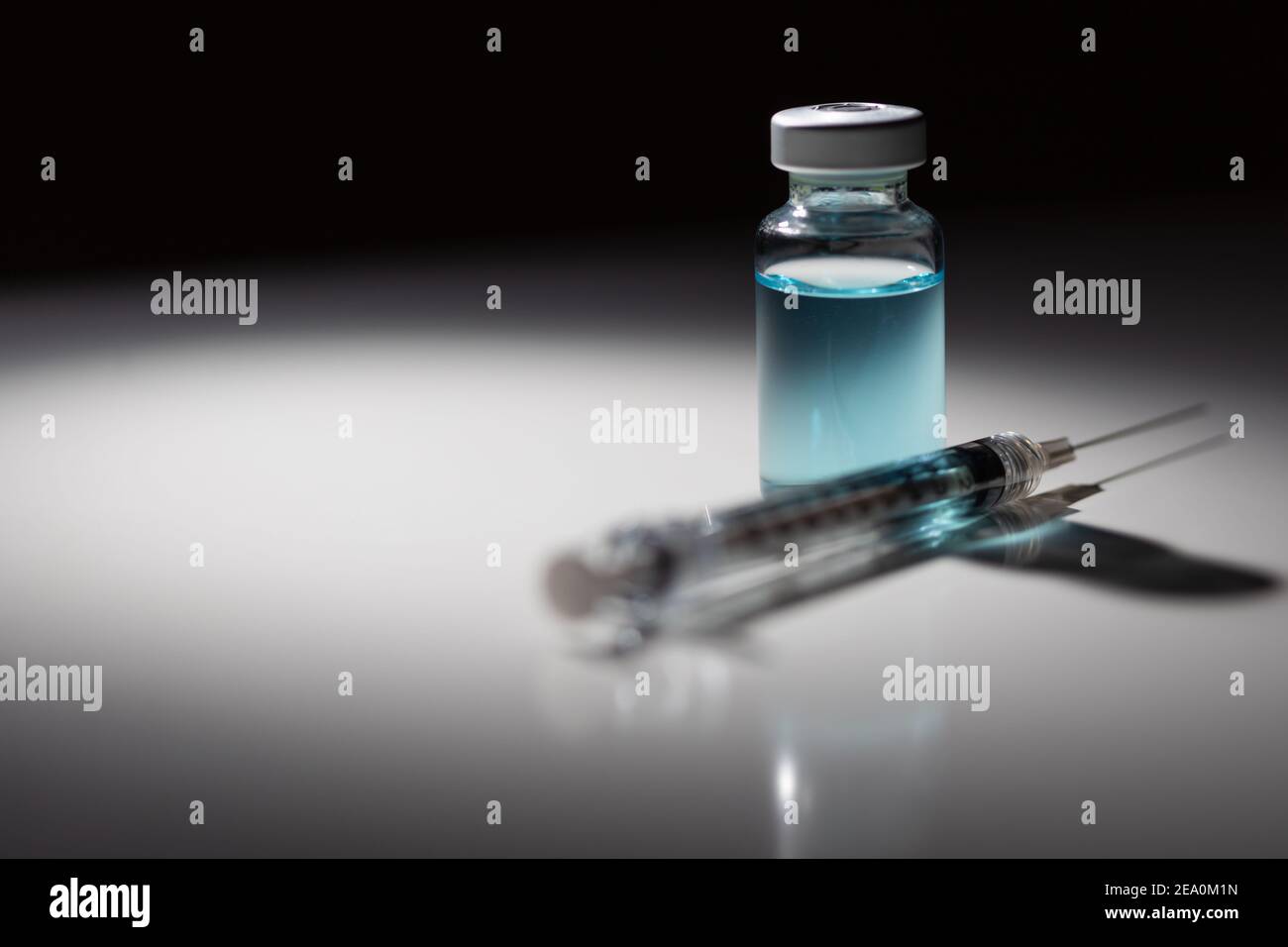 Syringe Needle and Medicine Vial With Light Blue Chemical Spot Lit on ...