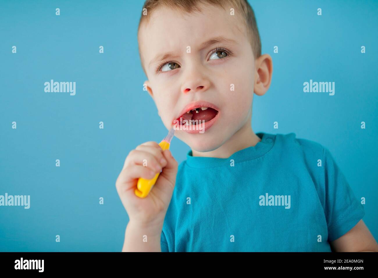 Little cute boy brushing his teeth on blue background Stock Photo - Alamy