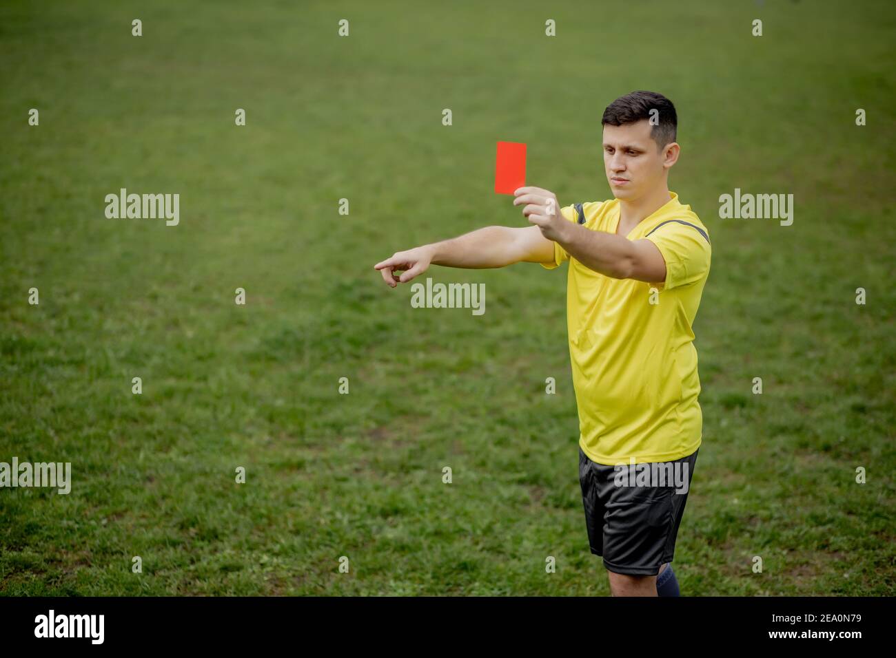 Angry football referee showing a red card and pointing with his hand on ...