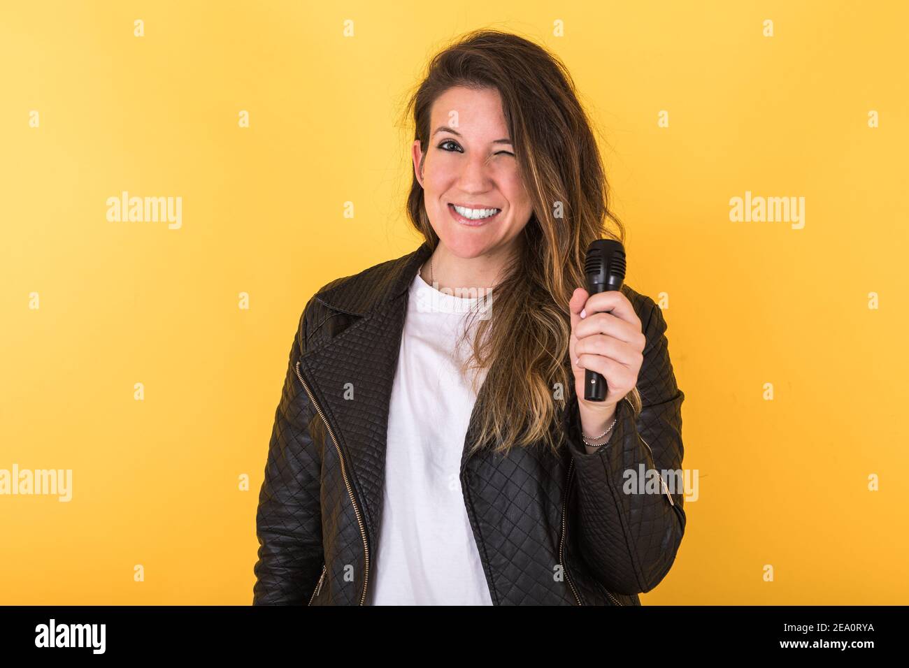 Young singer girl, wearing black leather jacket and microphone, winking ...