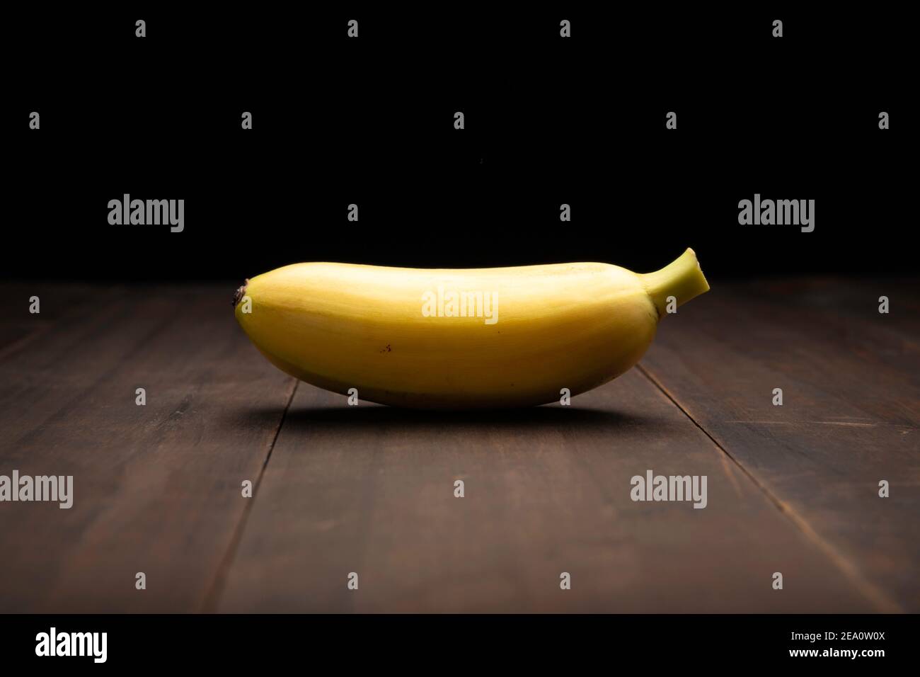 still life image of one tiny yellow banana close up on rustic wooden ...