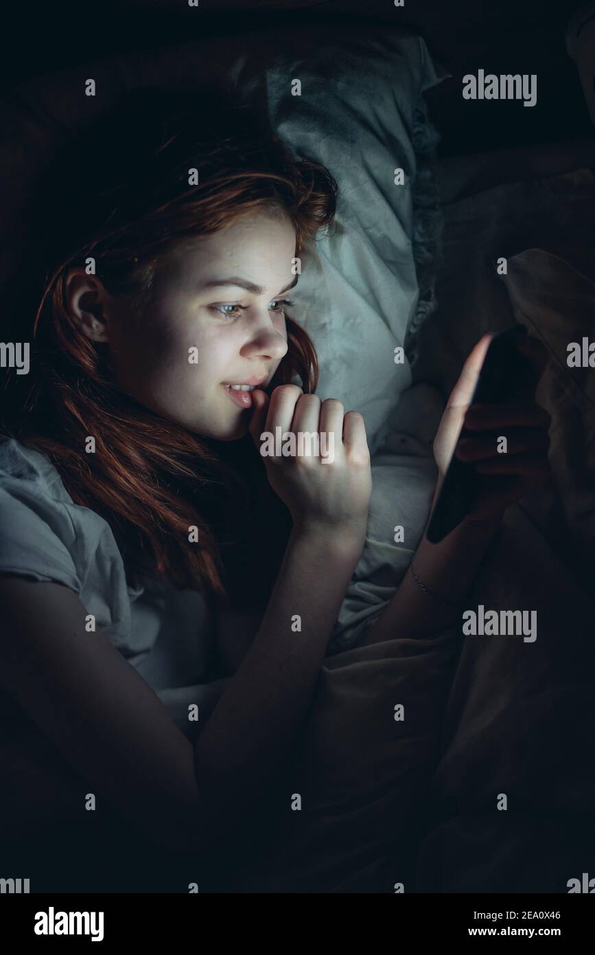 woman with a phone in her hands at night before bedtime emotions ...