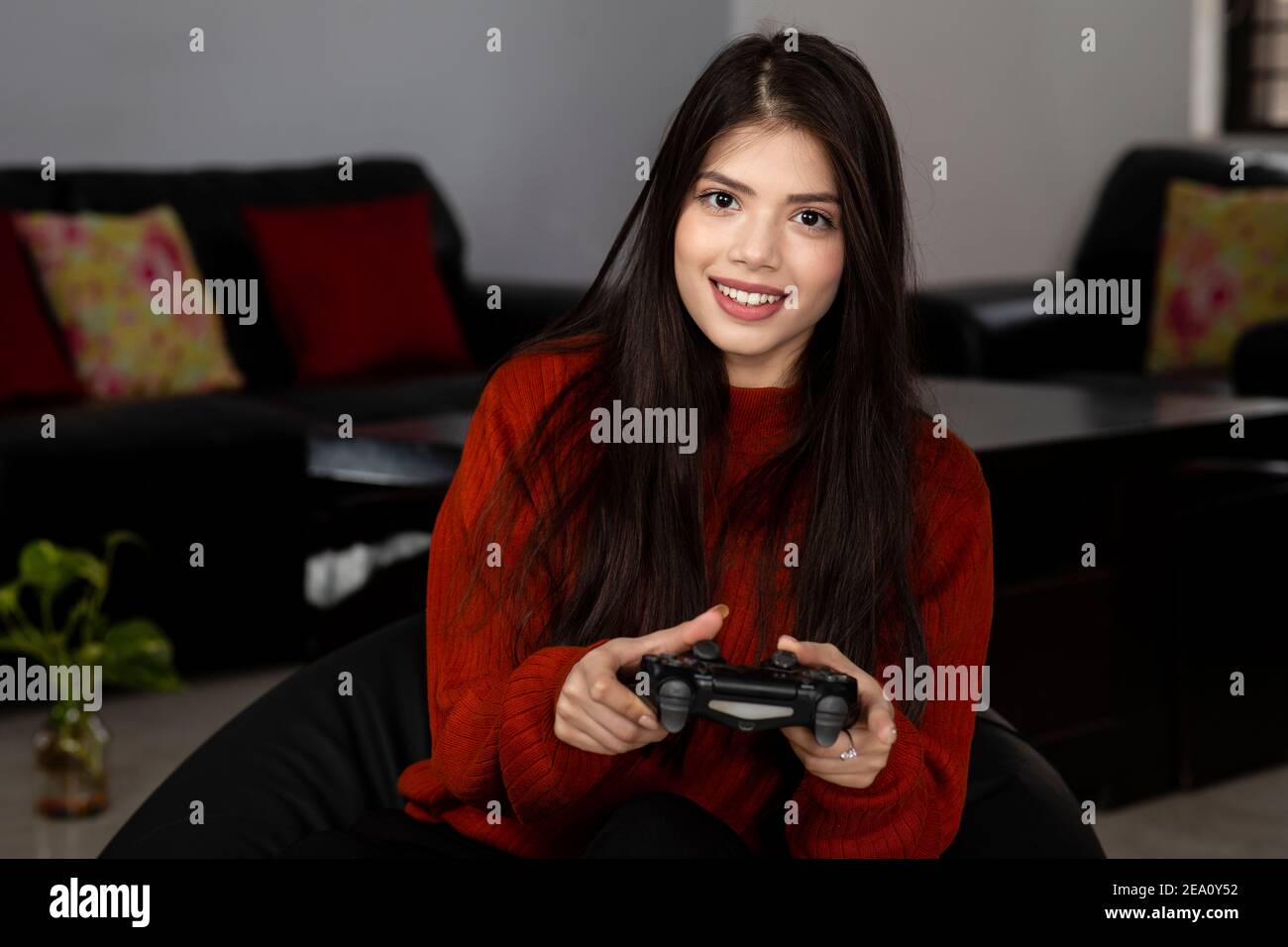 Pretty young woman holding game console in her hands sitting in her ...