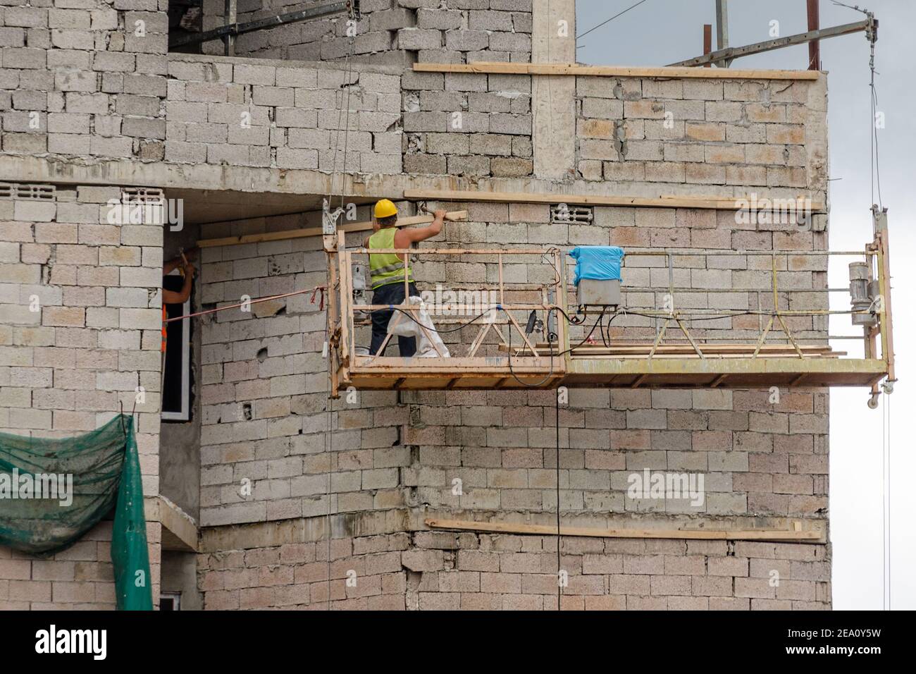 Construction worker at lifting platform works outside the cinder block ...
