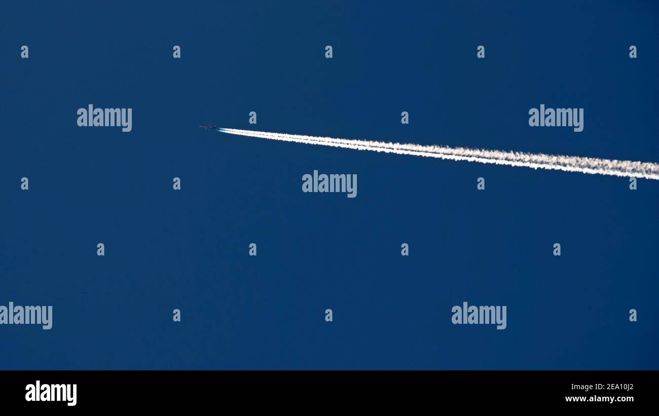 Jet contrails in c clear blue sky Stock Photo - Alamy