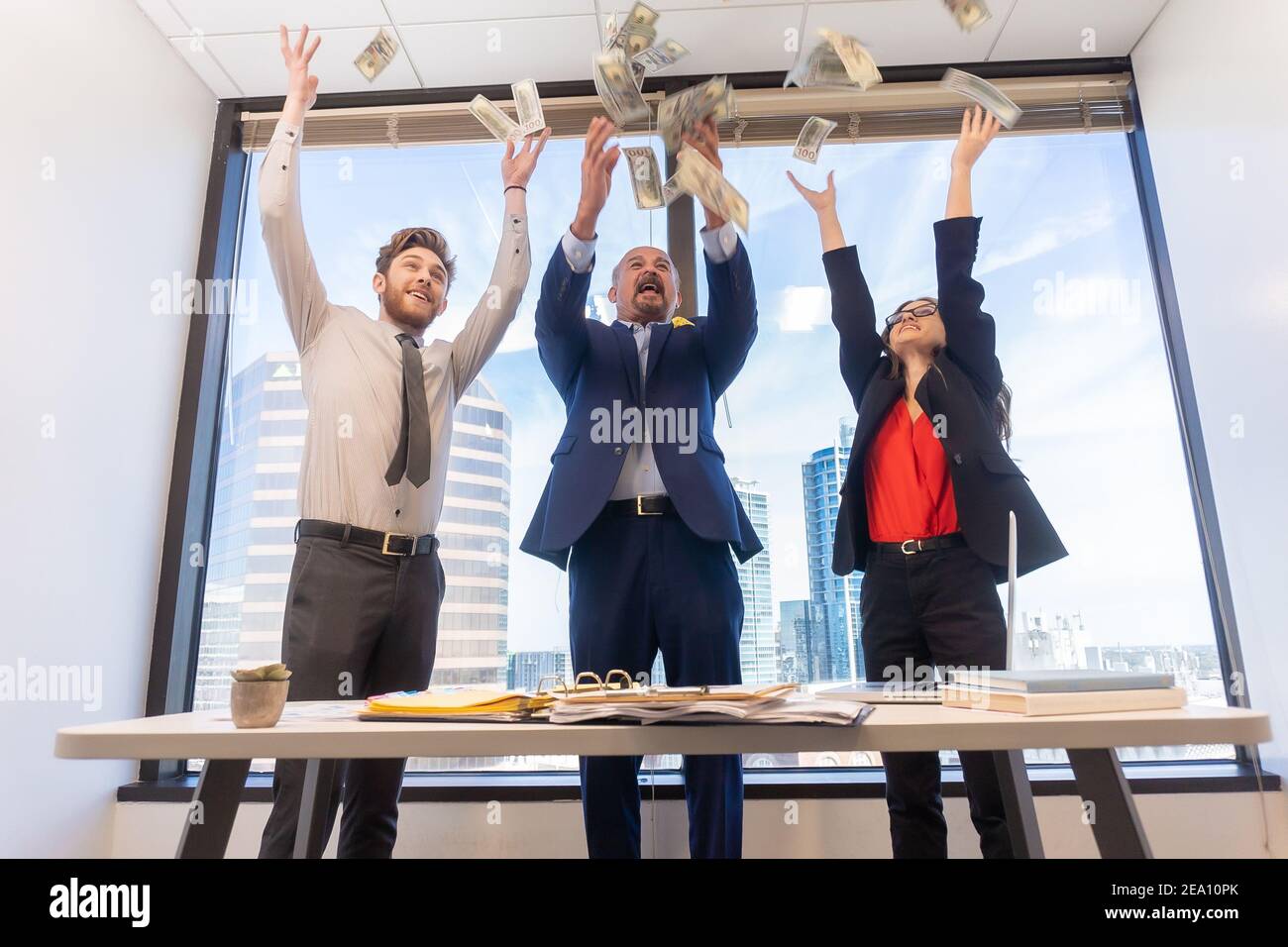 Employees celebrating business success with paper money Stock Photo - Alamy
