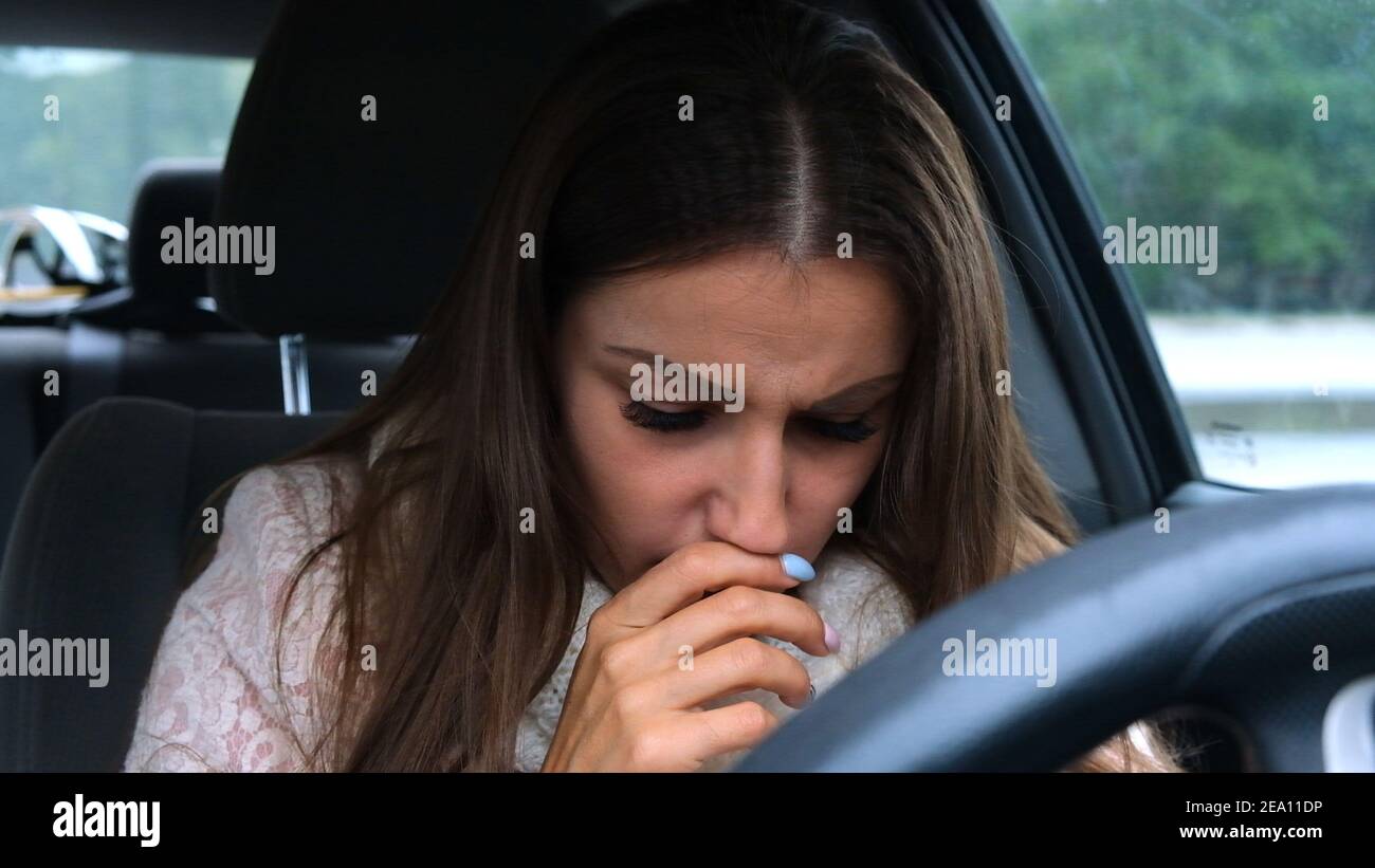 Sad and tired woman leaning her head on the steering wheel, crying ...