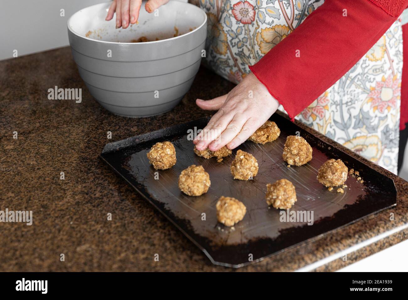 Middle aged women rolling anzac biscuit mixture on baking tray Stock ...