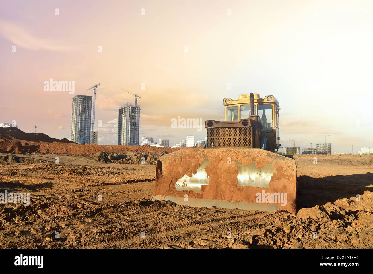 Dozer on earthmoving at construction site on sunset background ...