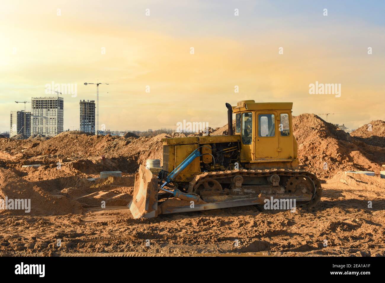 Dozer on earthmoving at construction site on sunset background ...