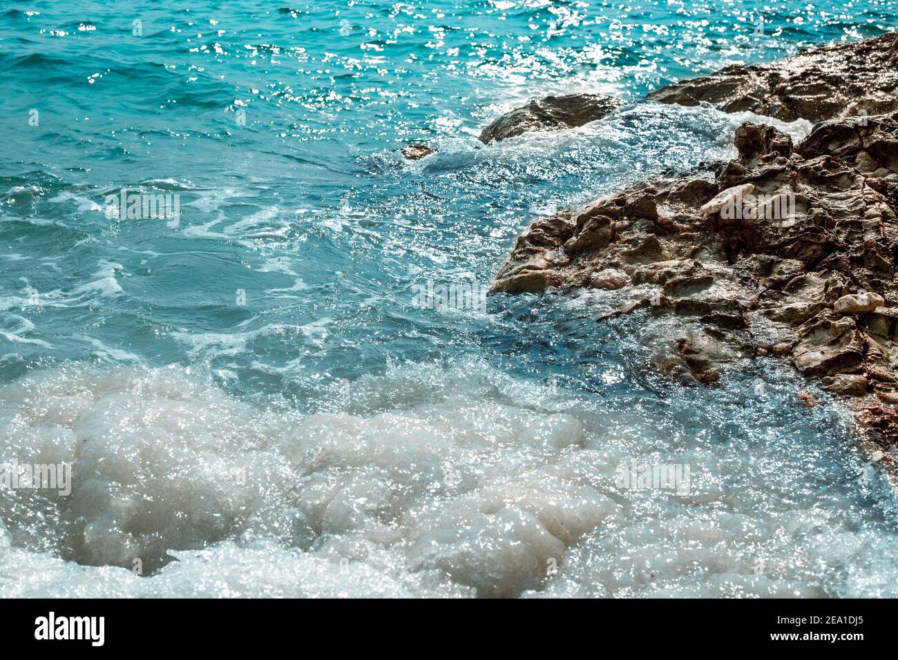 blue sea with foam from the waves and rocky shore Stock Photo - Alamy