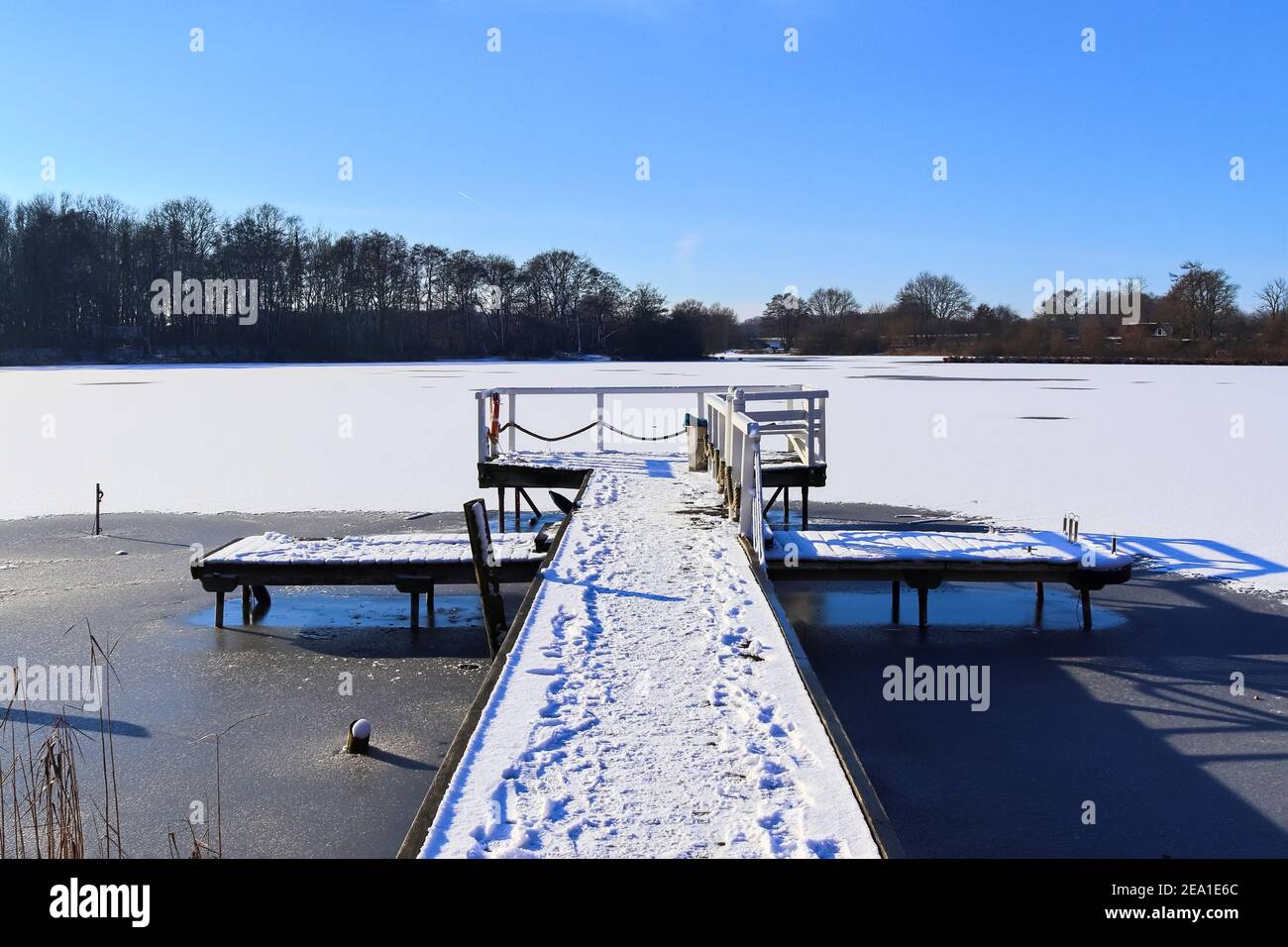 A snow covered wooden jetty at a frozen lake on a sunny day in ermany ...