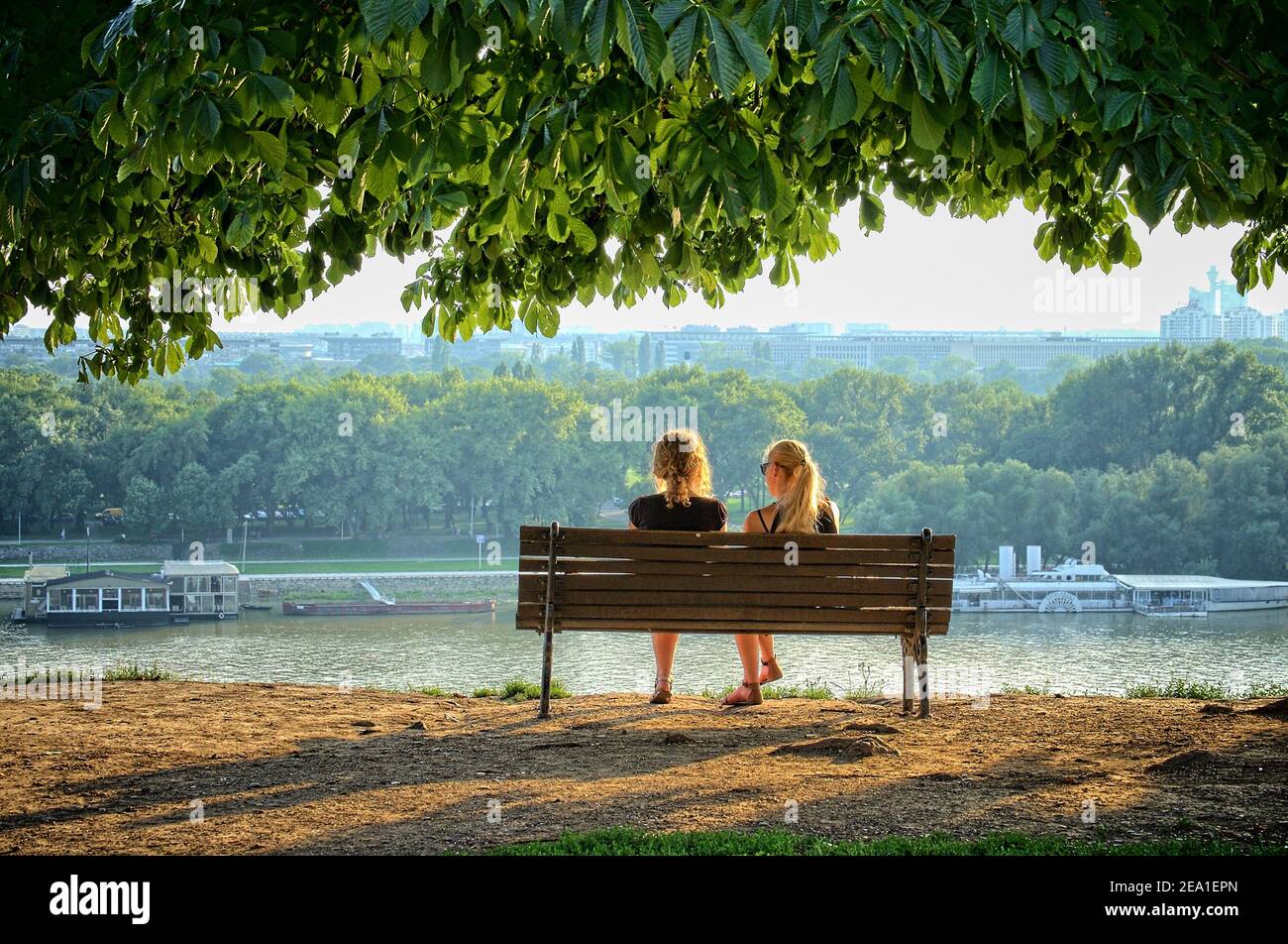 BELGRADE, SERBIA - JULY 29, 2014: two young women sitting on a bench of ...