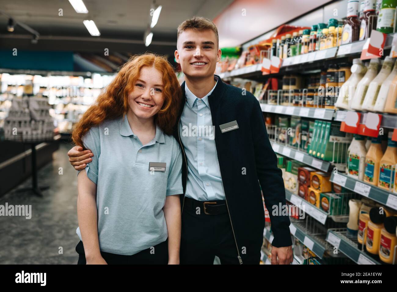 Portrait of two young workers standing together in supermarket. Male ...