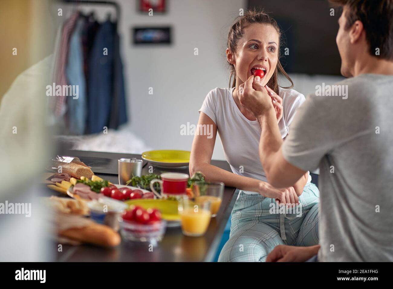 A young happy girl feeding by her boyfriend in a cheerful atmosphere at ...