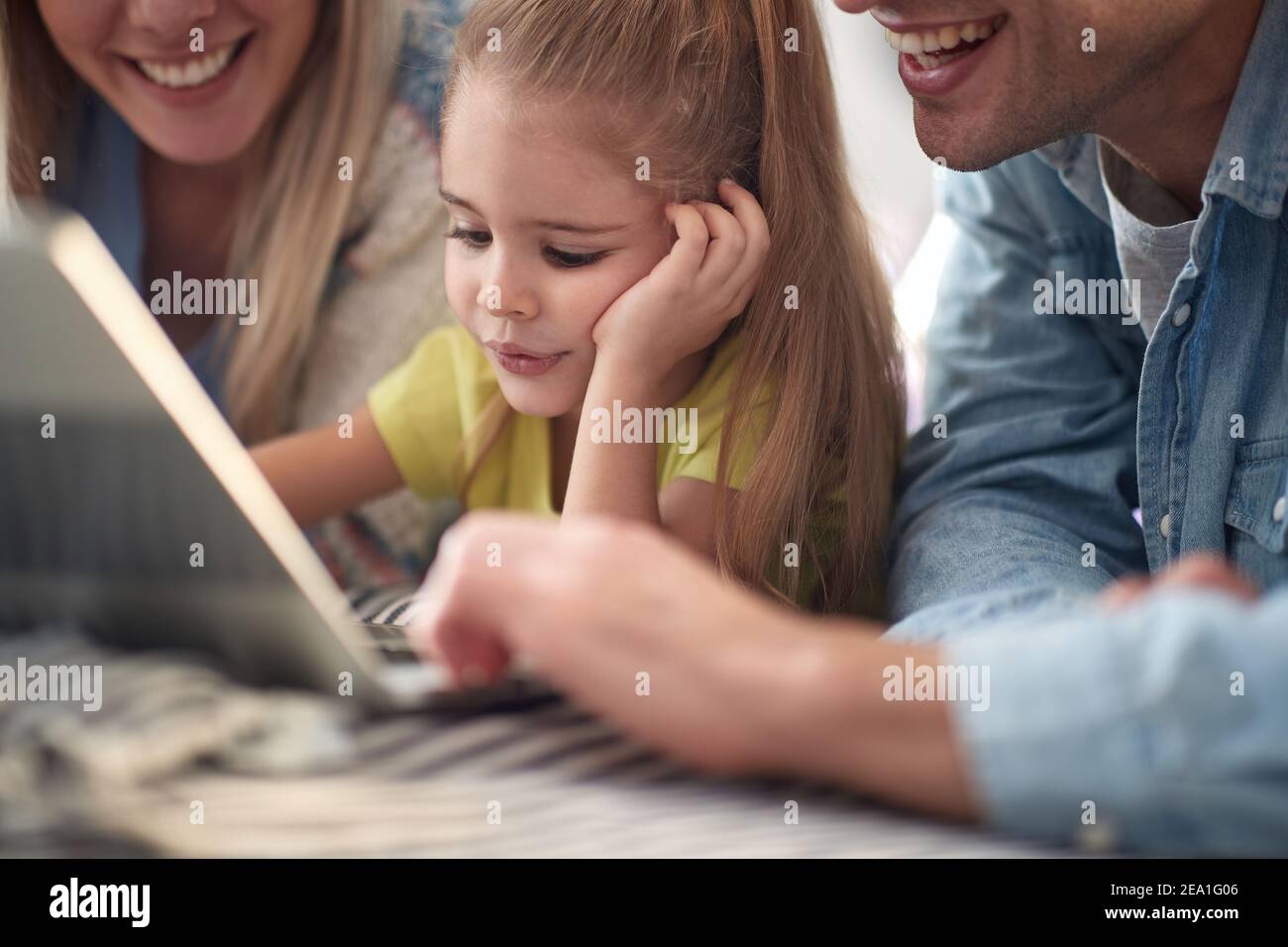 A little daughter in a relaxed atmosphere at home learning how to use a ...