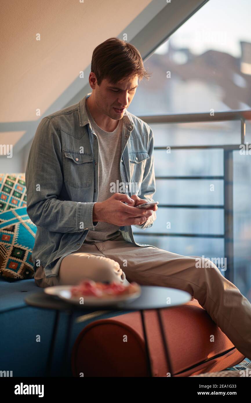 A young guy chatting on the smartphone while resting in a pleasant ...