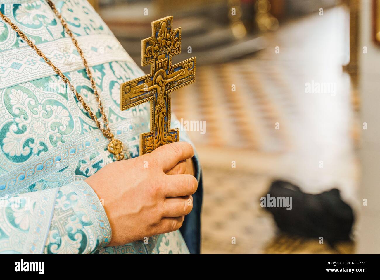 Holy father in his robe with a golden cross in his hands in church ...