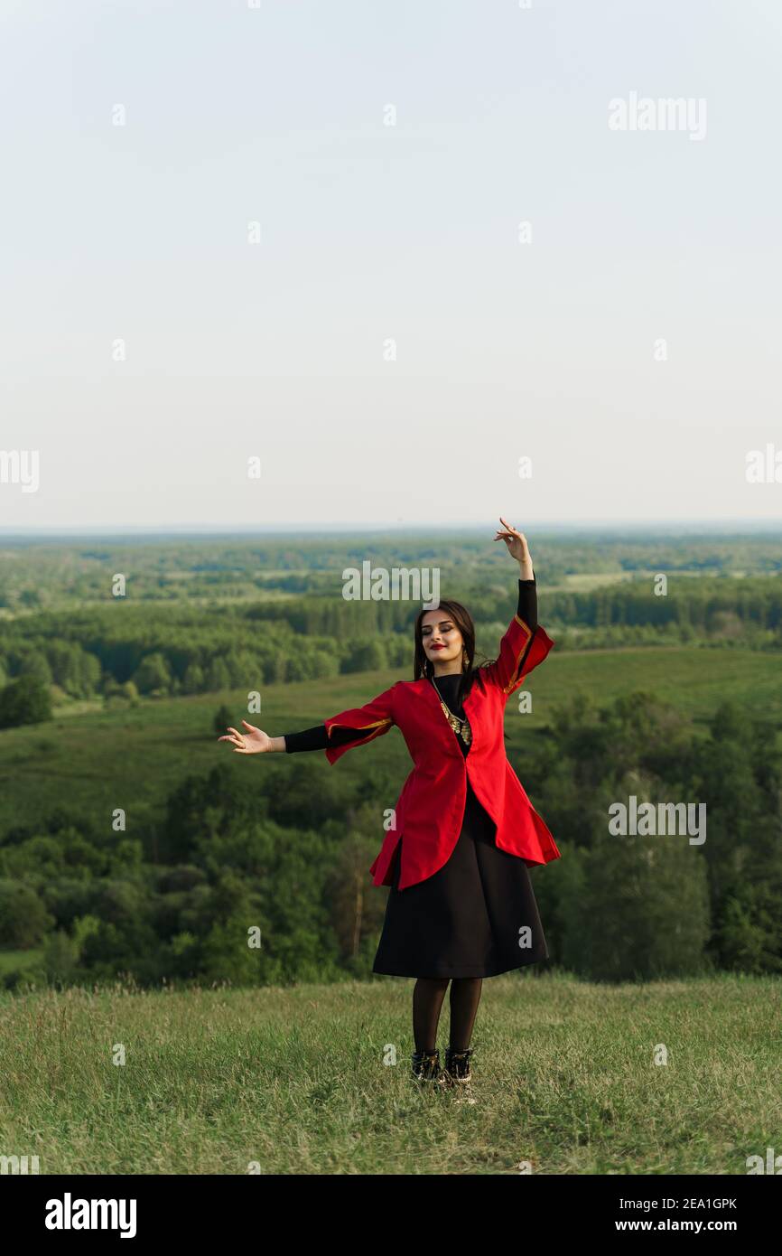 Georgian woman dances national dance in red national dress on the green ...