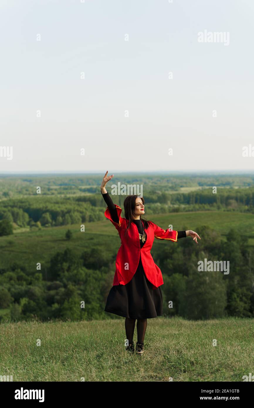 Georgian woman dances national dance in red national dress on the green ...