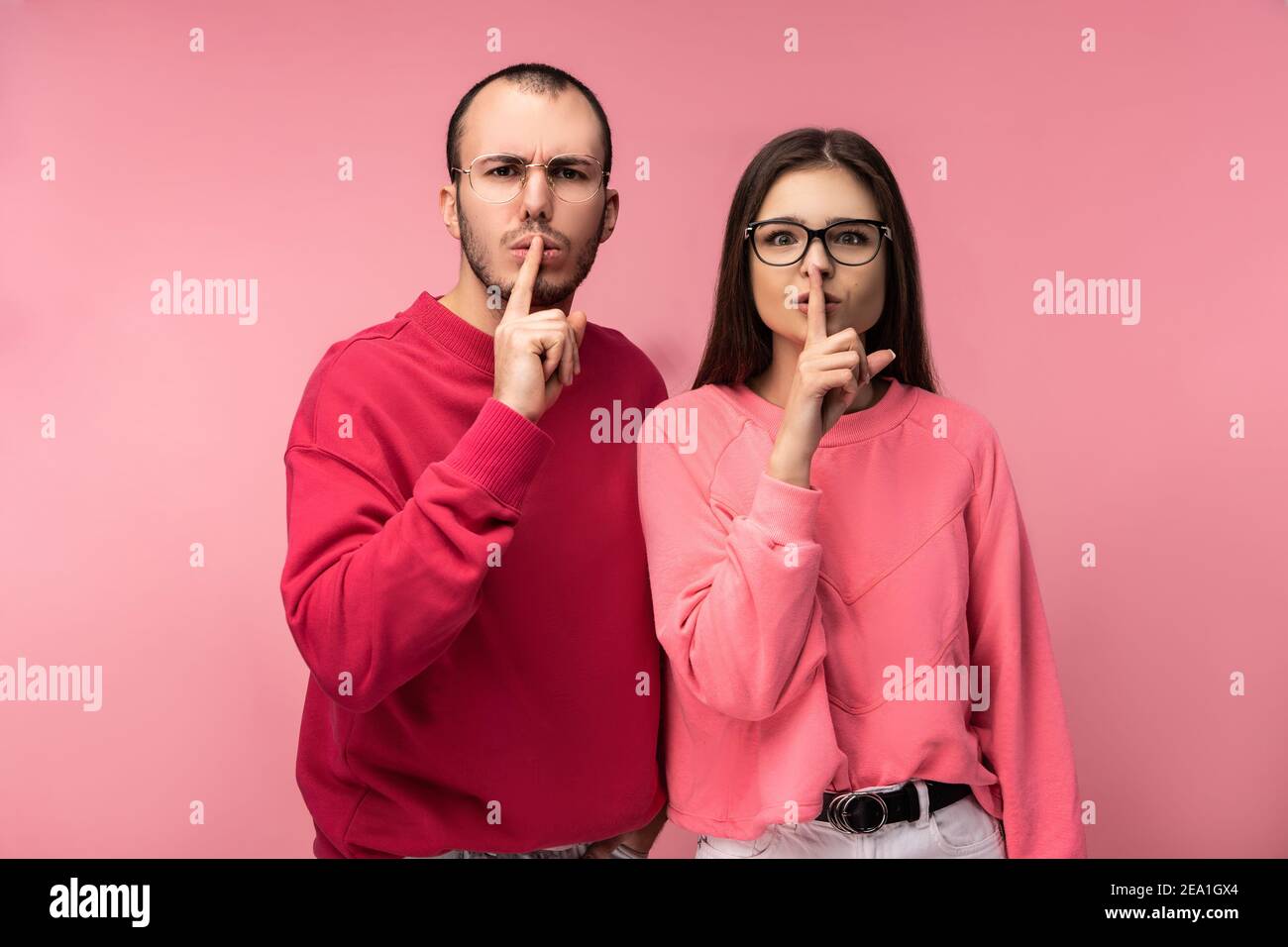Photo of sweet couple in glasses stands and shows shhh. Male and female ...