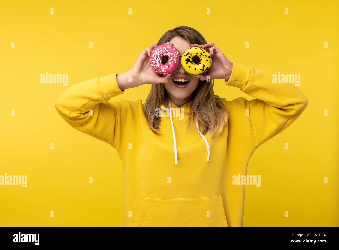 Photo of attractive lady holds donuts and covered eyes up and smiles ...