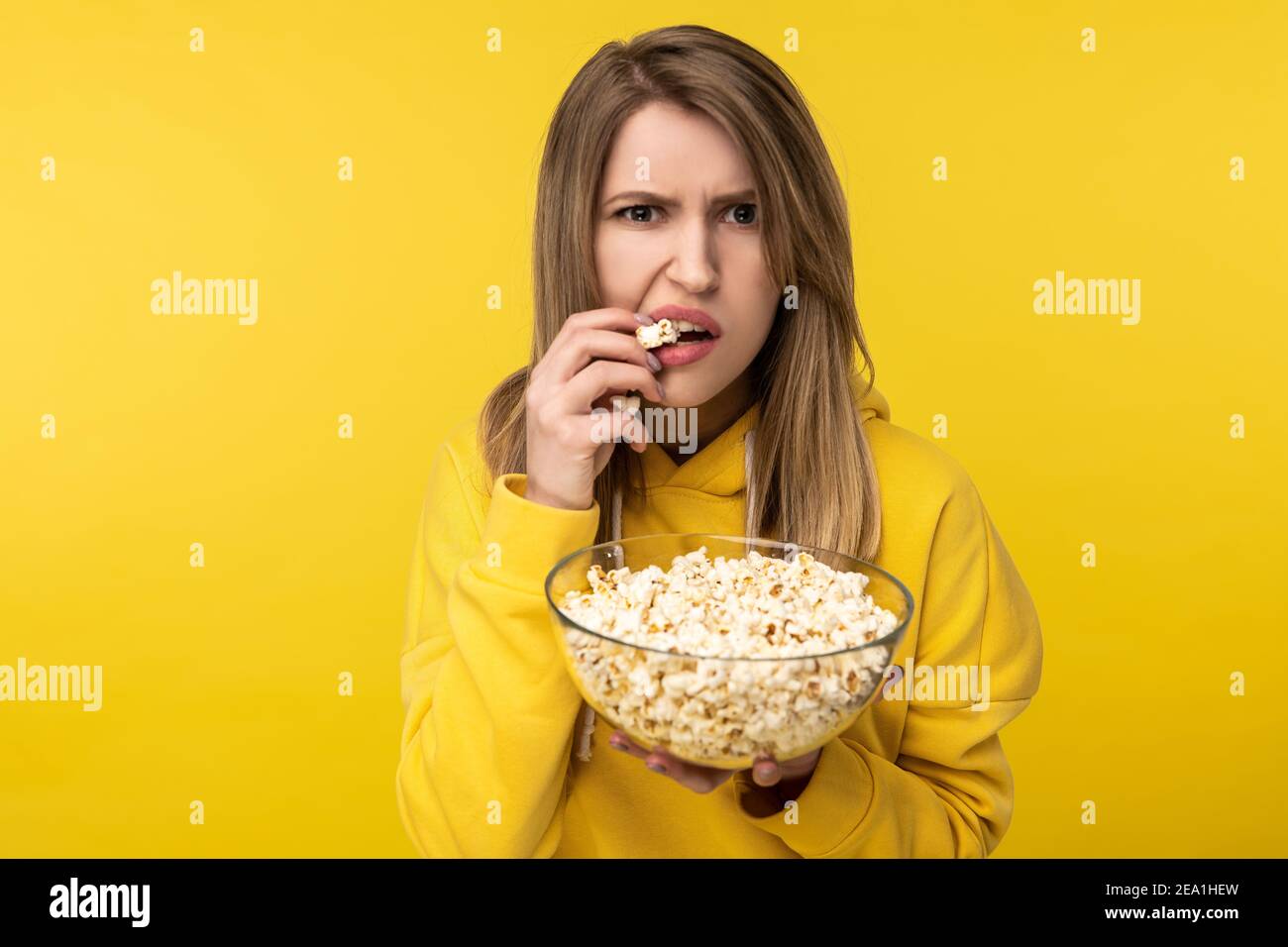 Photo of attractive lady holds plate of popcorn, eats it with ...