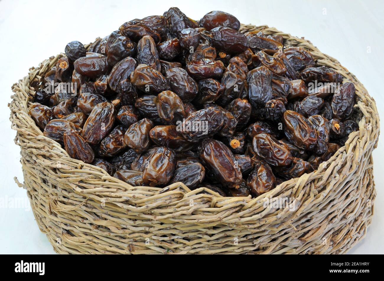 A pile of dried dates in a basket on white background Stock Photo - Alamy