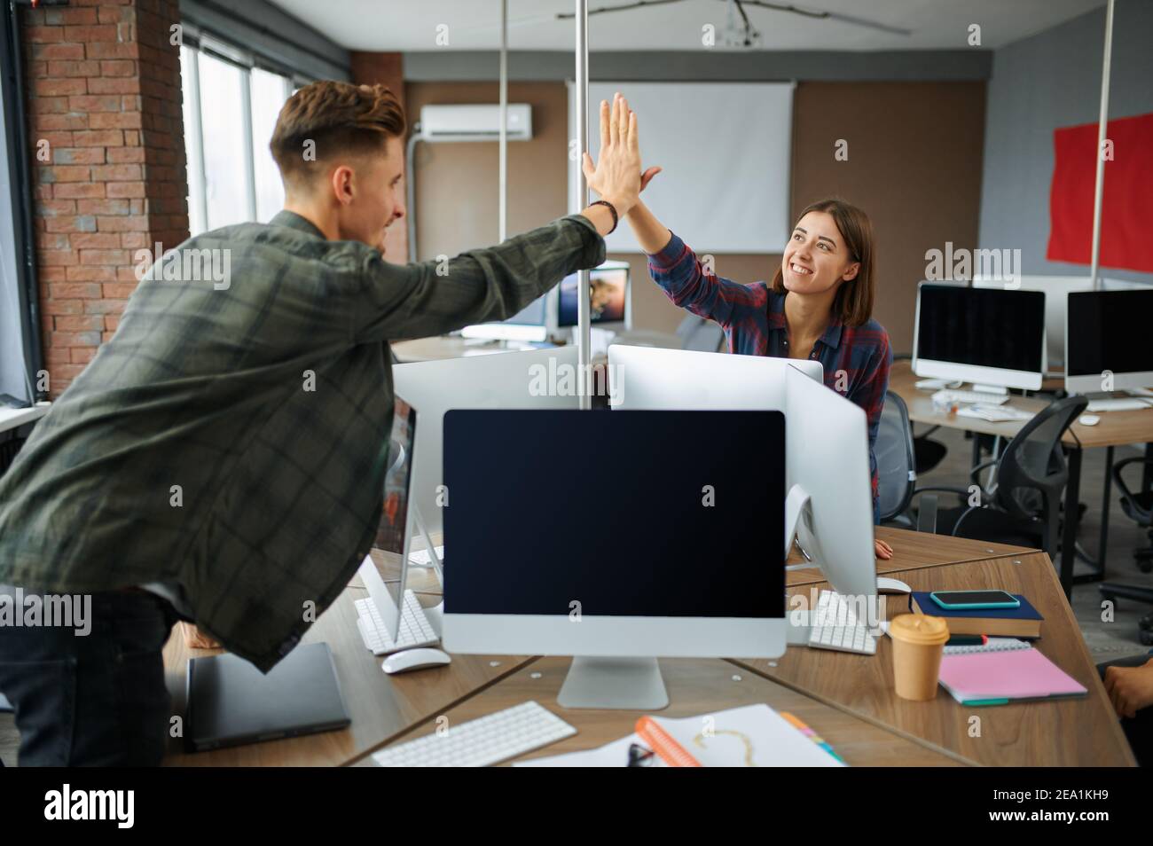 IT specialists high-five each other in office Stock Photo - Alamy
