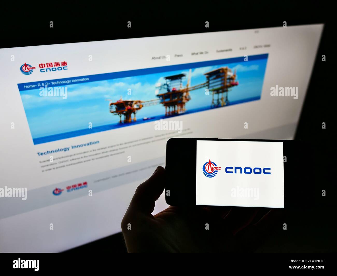 Person holding mobile phone with logo of China National Offshore Oil ...