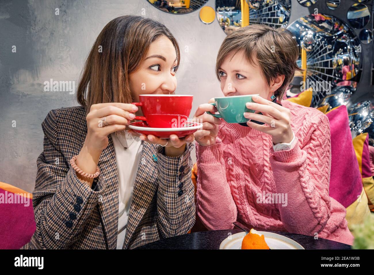 Funny girls friends drink coffee in a cafe and chat and gossip about ...