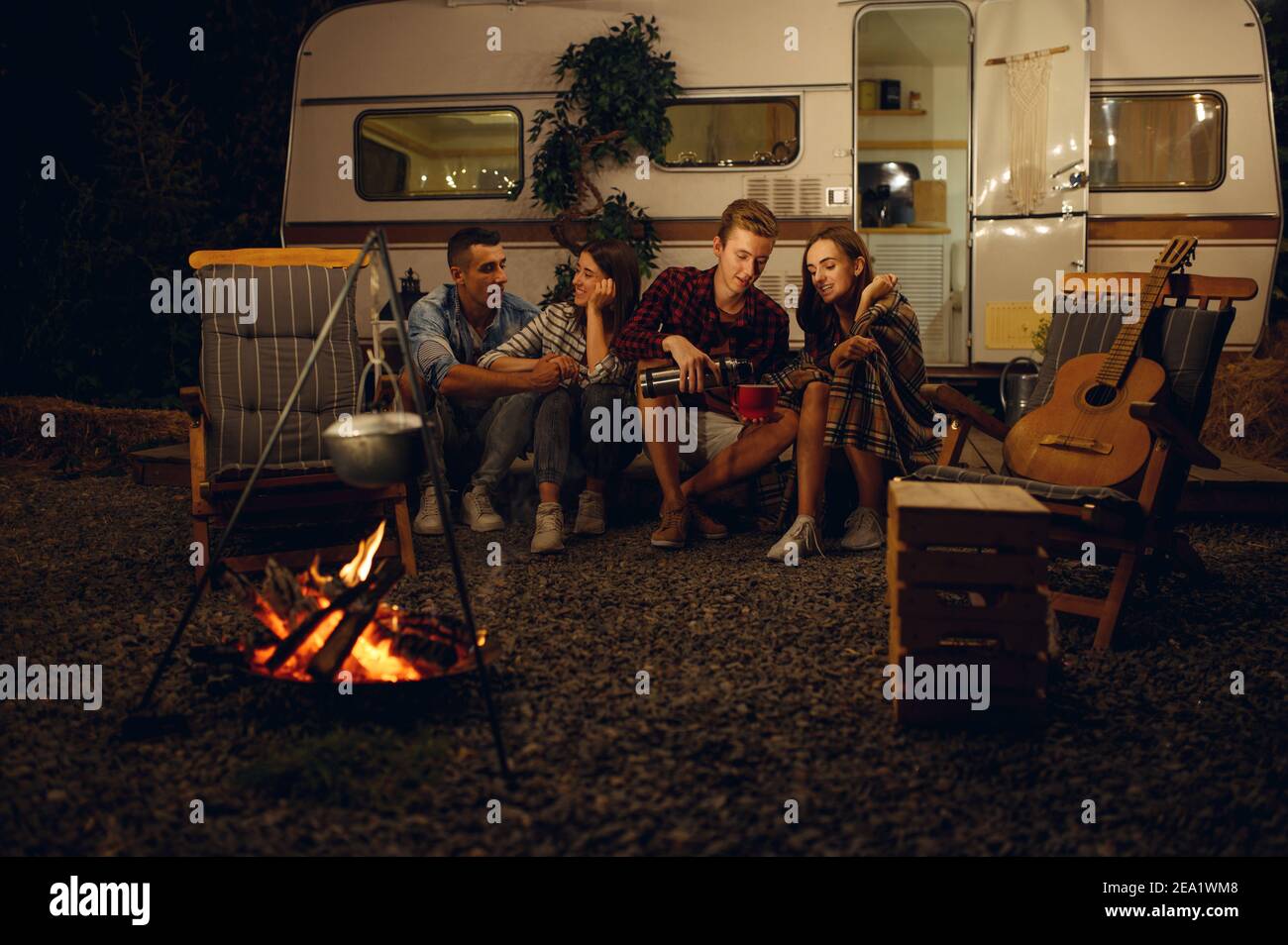 Friends sitting by campfire in the night, camping Stock Photo - Alamy