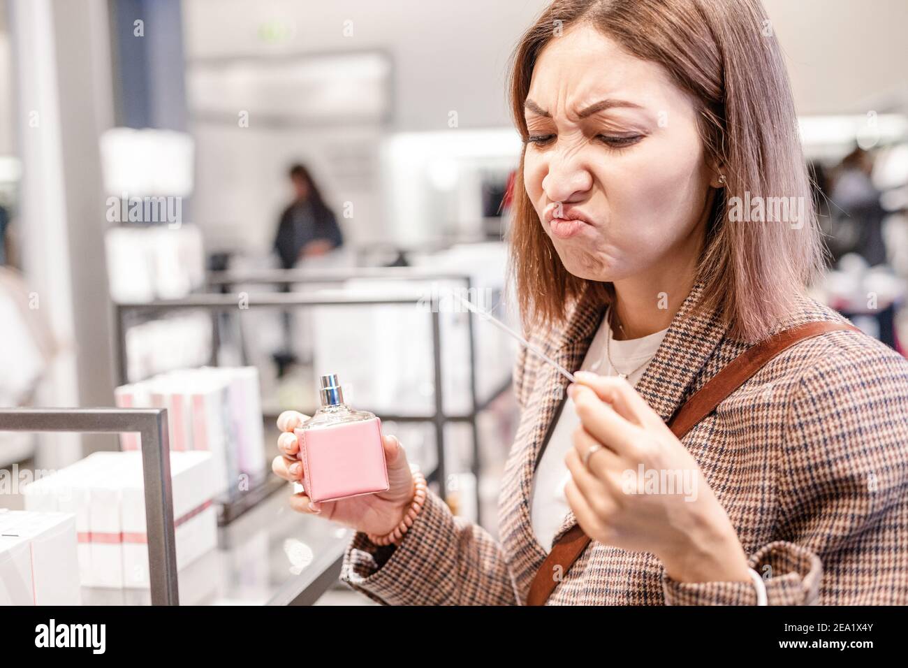 Asian woman sniffs perfume with a disgusting and terrible fragrance ...