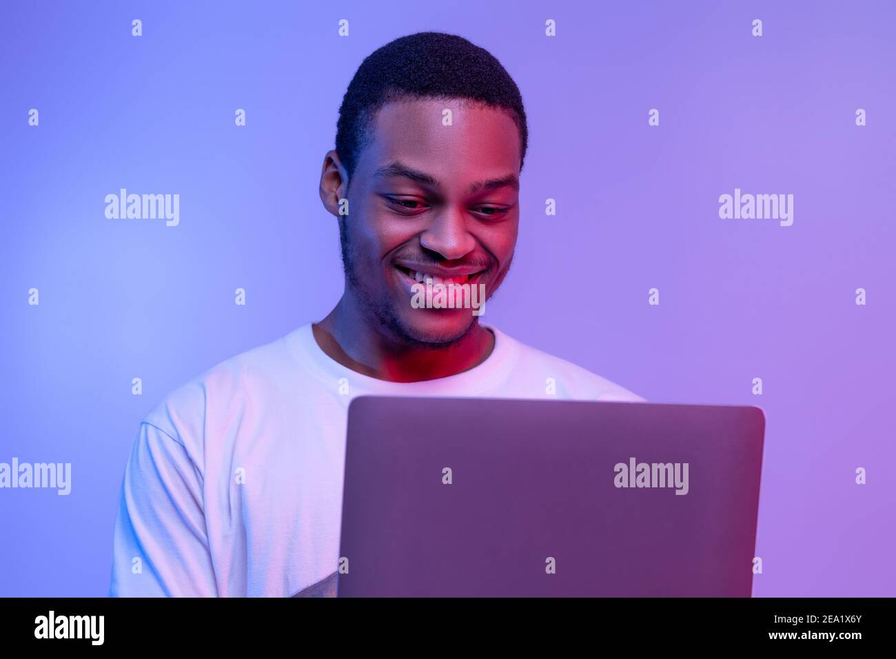 Handsome Smiling Black Programmer Guy Working Online On Laptop In Neon ...