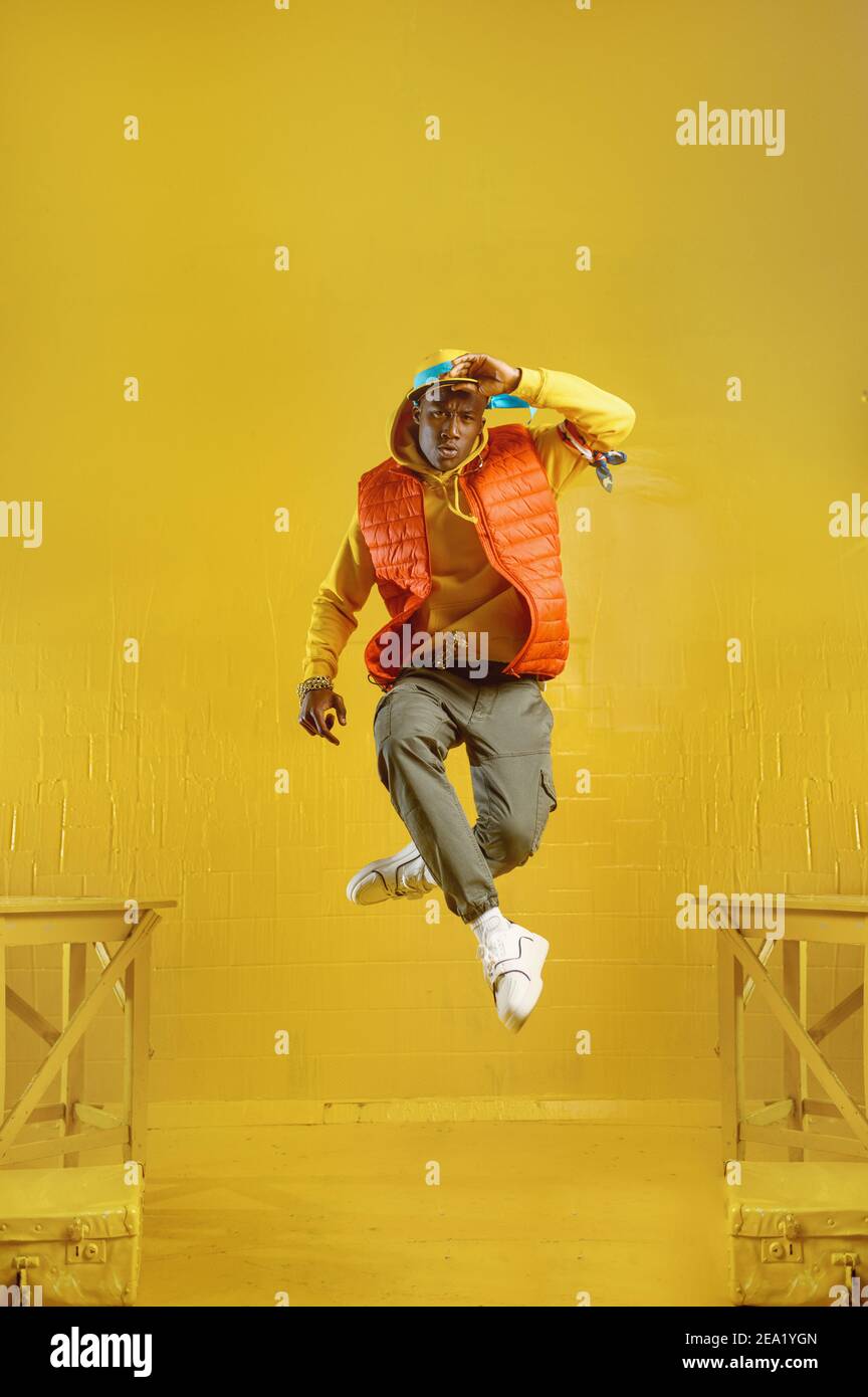 Young rapper jumps in studio with yellow tones Stock Photo - Alamy