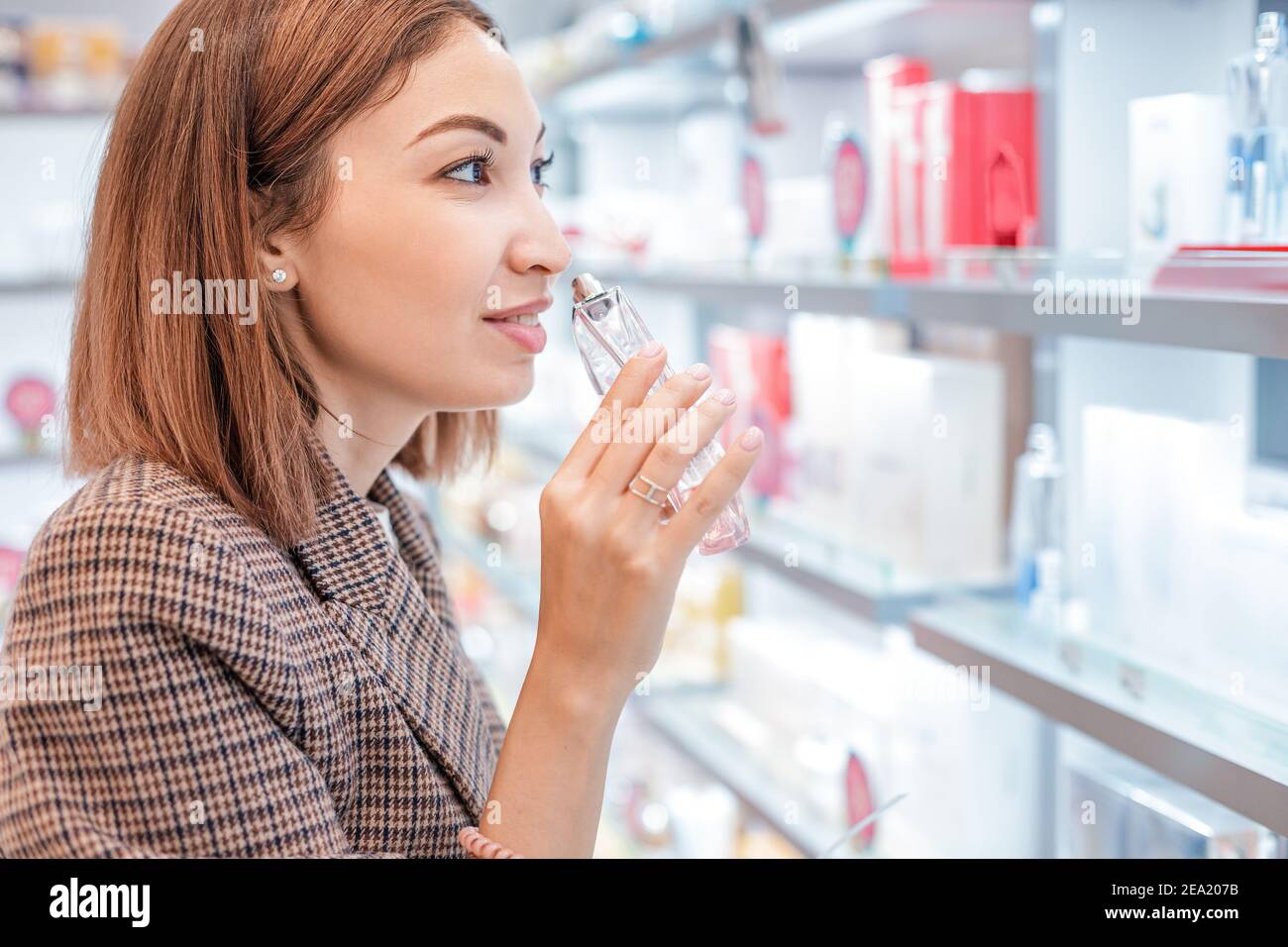Asian woman in a perfume store tests and sniffs a new perfume fragrance ...