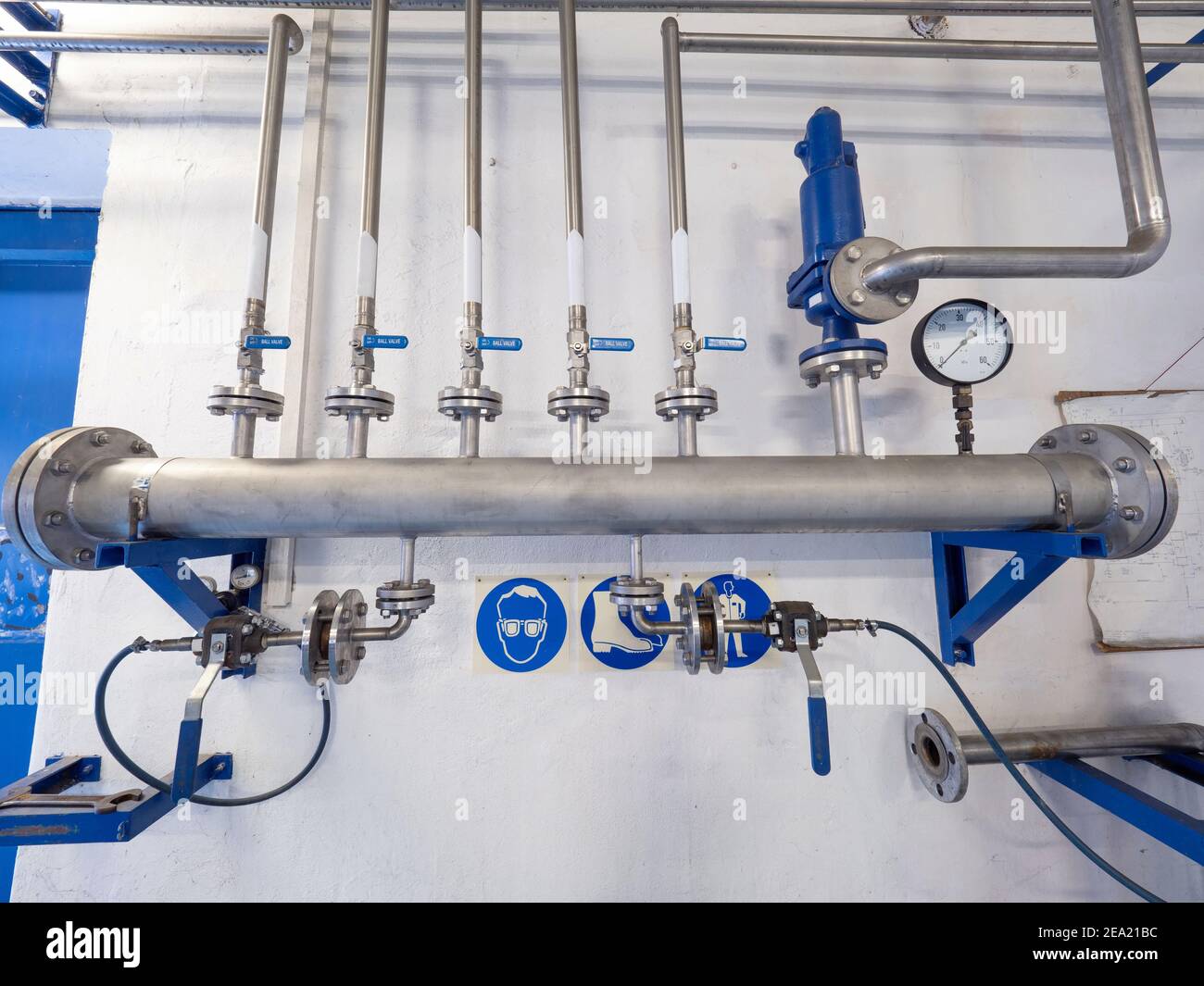 Chrome steel gas pipes with ball valves and fittings on the wall. The ...